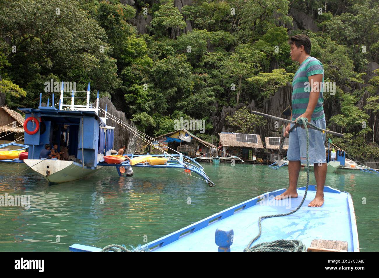 Man on the bow of a tourist boat preparing to throw anchor overboard ...