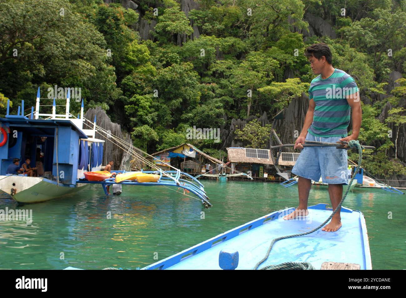 Man on the bow of a tourist boat preparing to throw anchor overboard ...