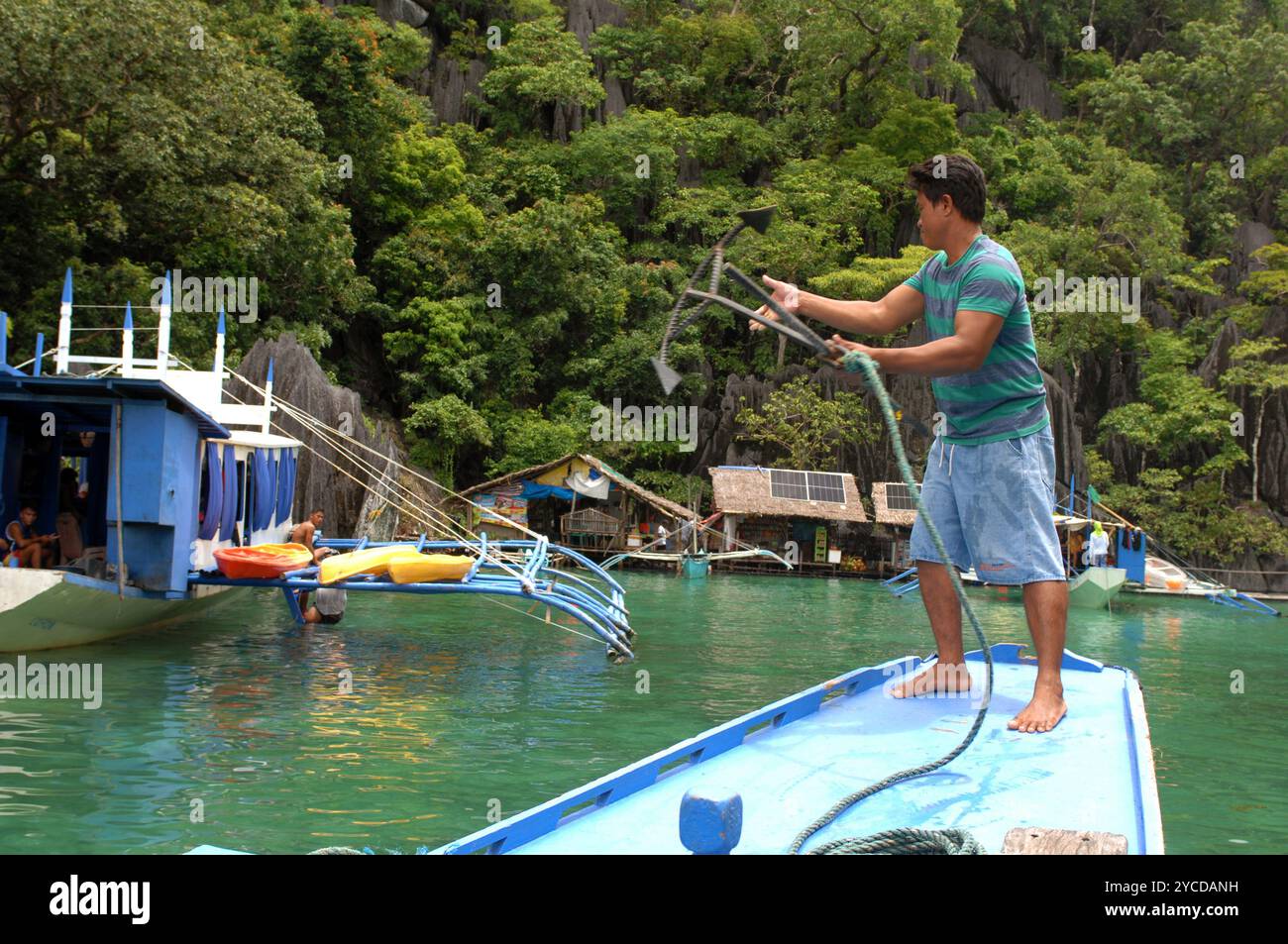 Man on the bow of a tourist boat preparing to throw anchor overboard ...