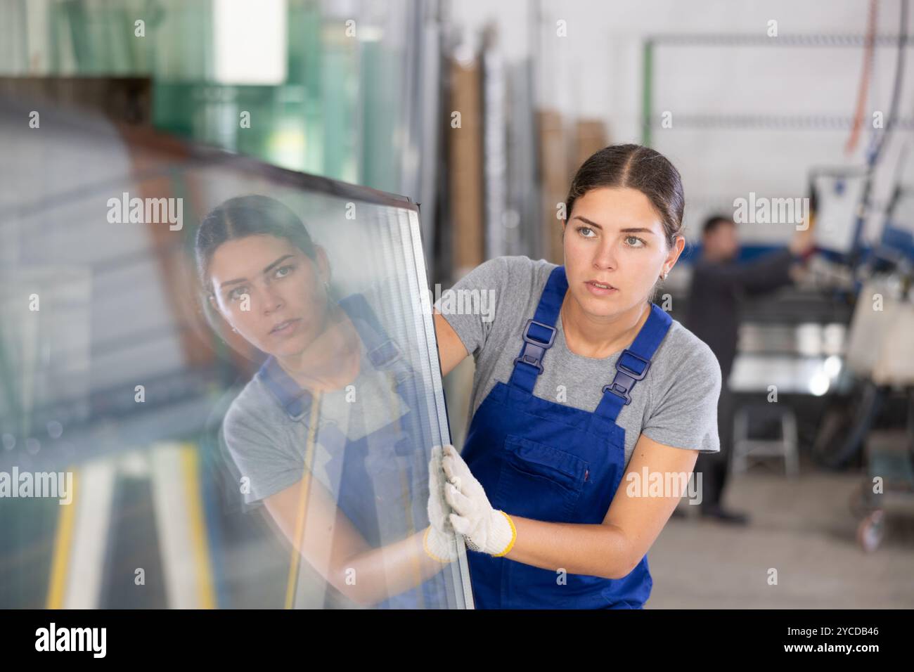 Female employee pushing A-frame with insulated glass units at factory ...