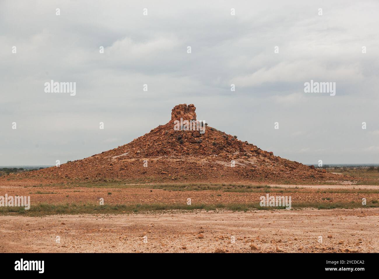 A prominent rock formation rises sharply from the flat terrain of ...