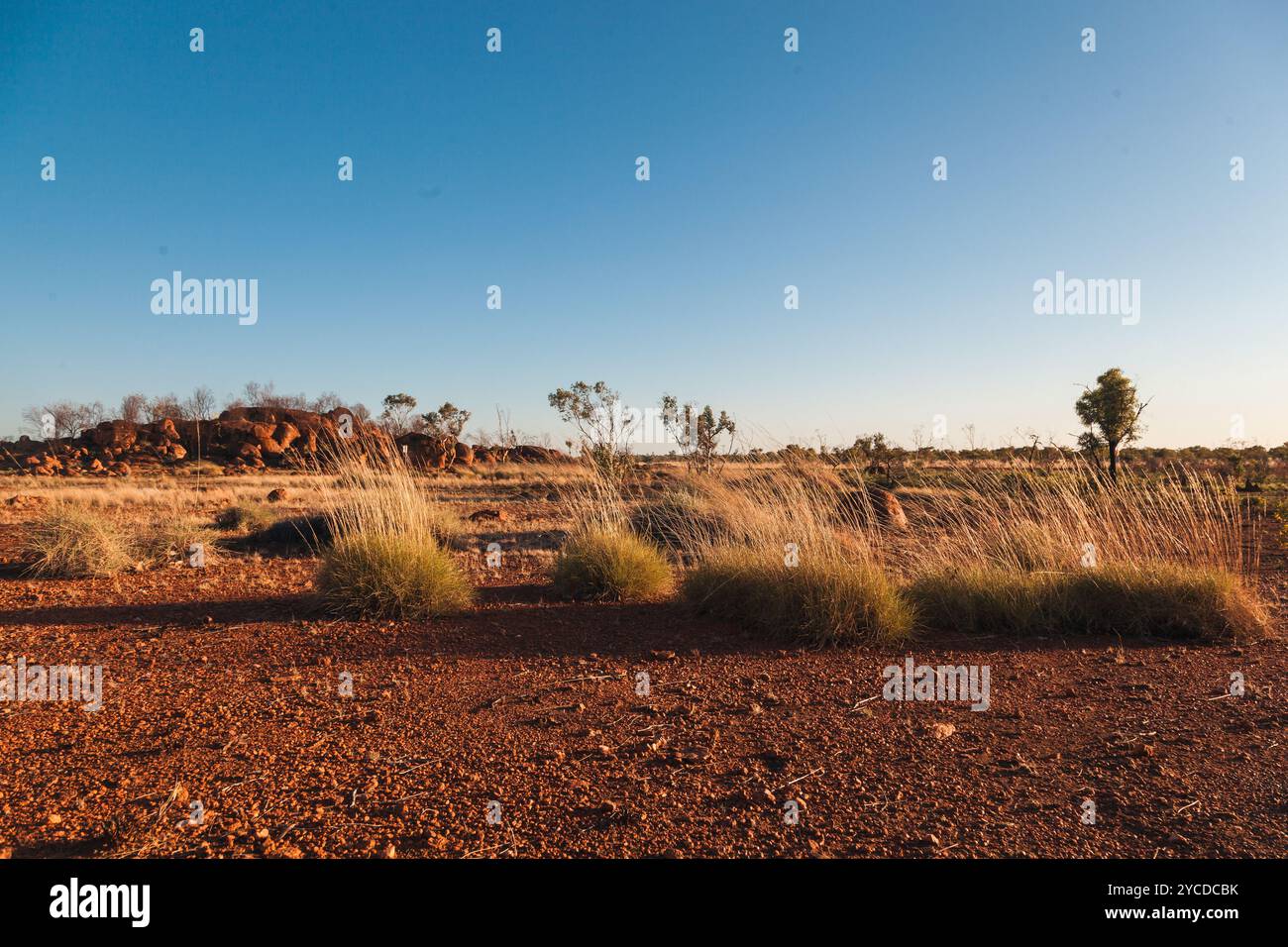 Golden hour casts a warm glow over the rugged Outback terrain in ...