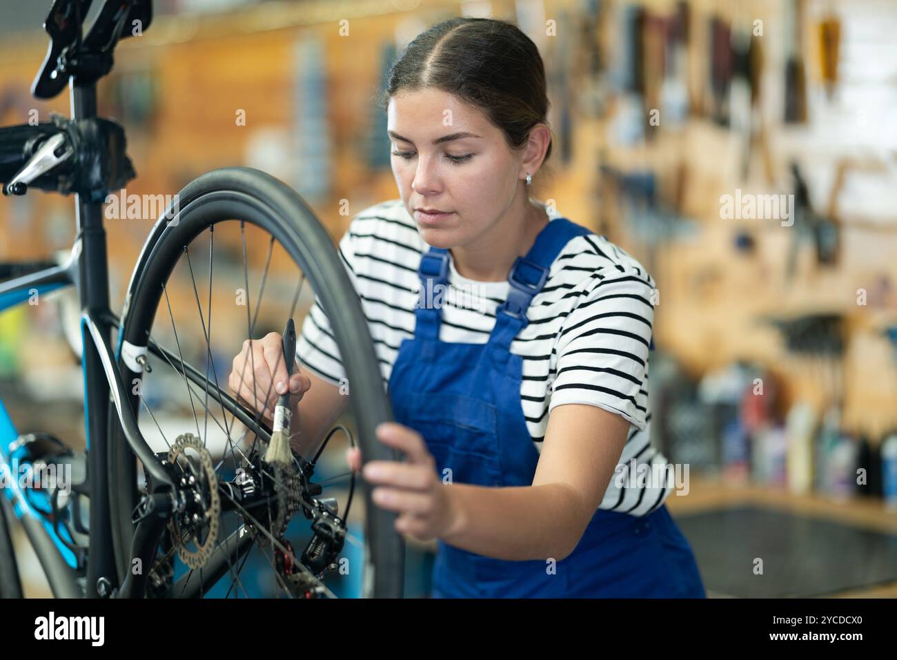 Female mechanic adjusting bicycle wheel in professional repair shop ...