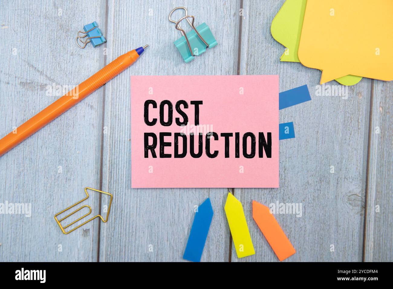 Top view calculator,banknotes and brown card with text COST REDUCTION ...