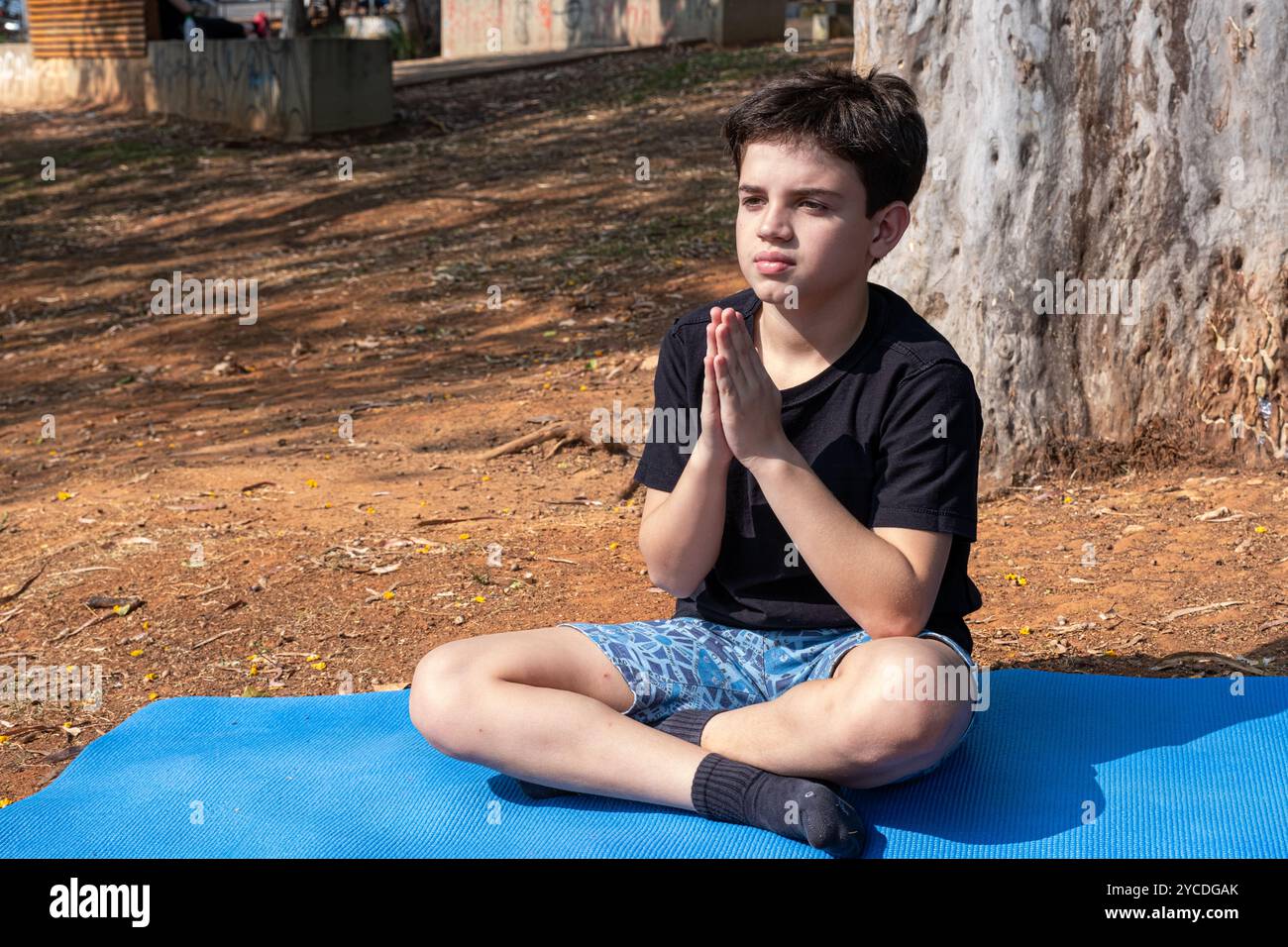 Brazilian child sitting on yoga mat and practicing breathing in outdoor ...
