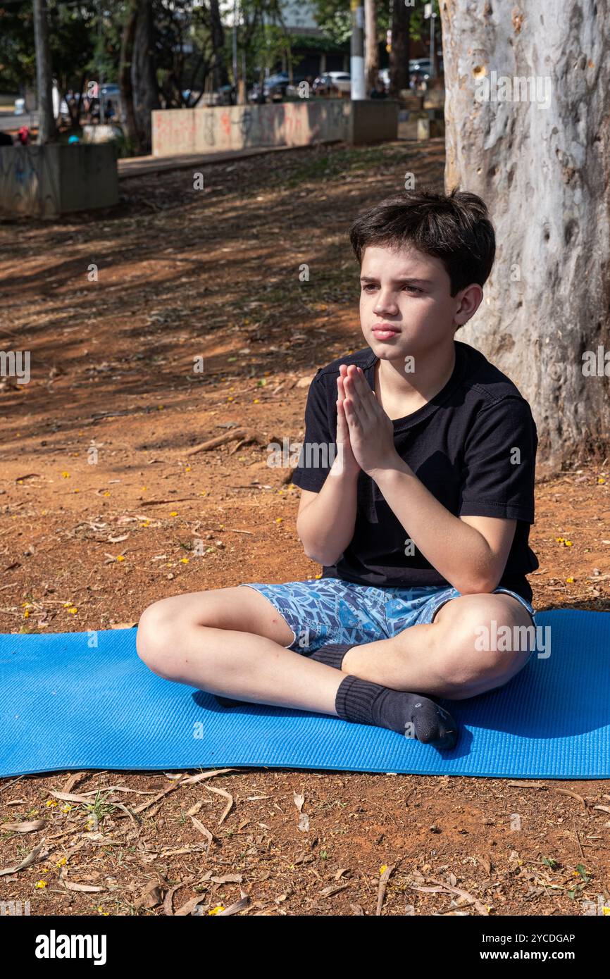 Brazilian child sitting on yoga mat and practicing breathing in outdoor ...