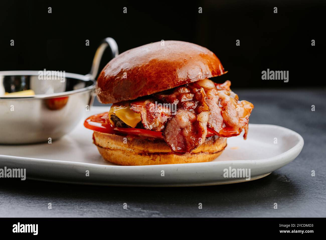Juicy bacon cheeseburger with fries served on a stylish plate, perfect ...