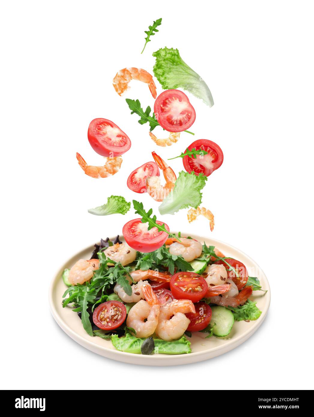 Shrimps and other ingredients falling onto plate on white background ...