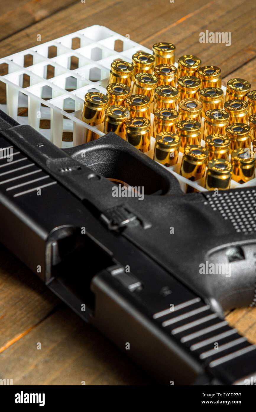 SIngle pistole with its action open next to a box of 9mm PARA ammuniton ...