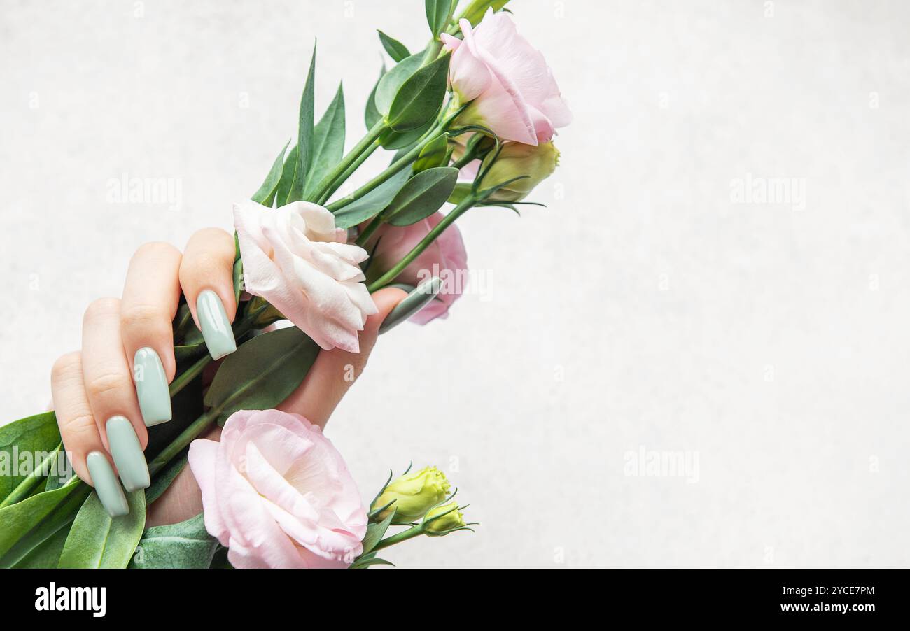 A slender hand showcases long pastel-colored nails while gently ...