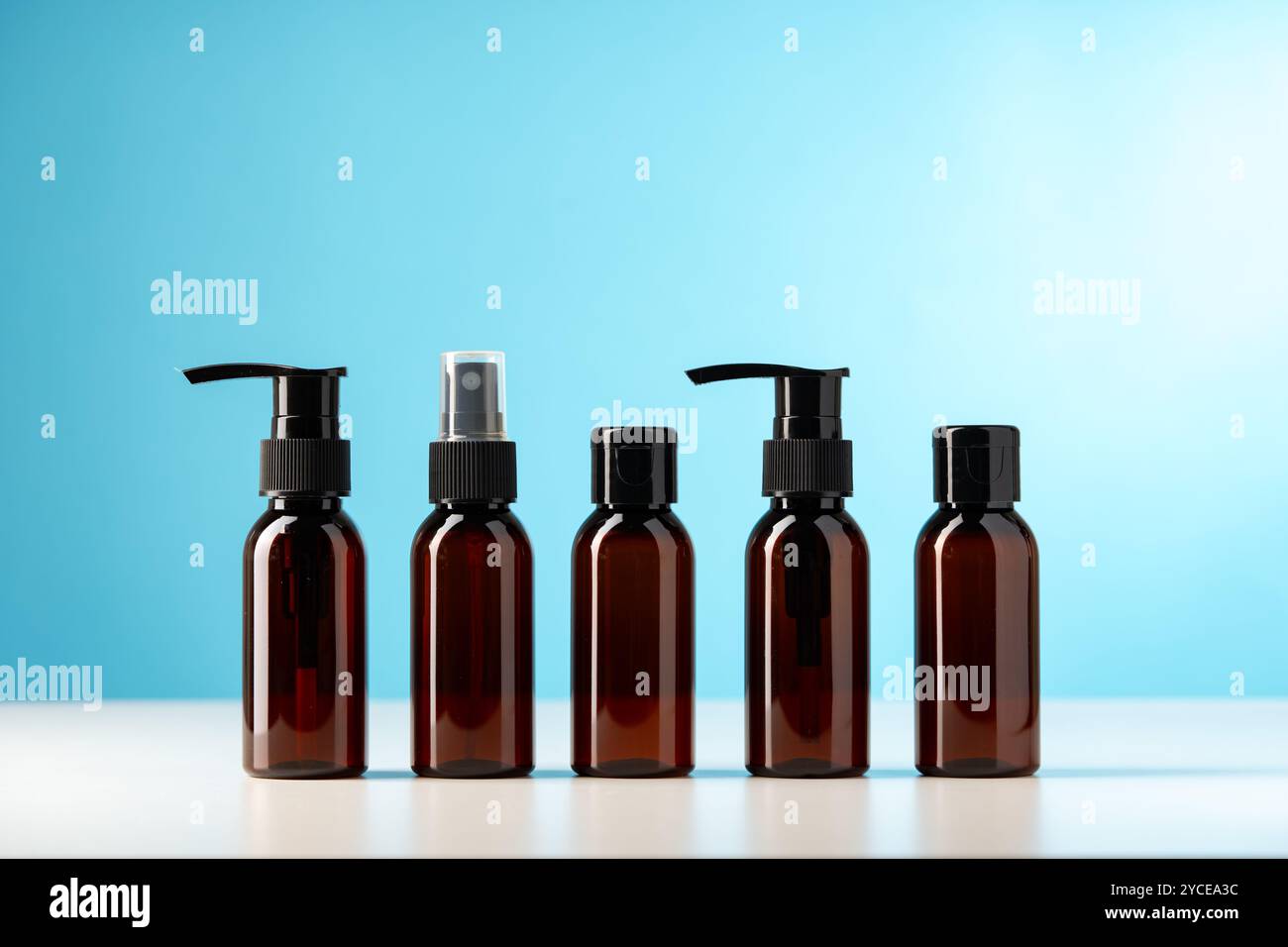 Collection of amber glass bottles with pumps and spray tops on a light ...