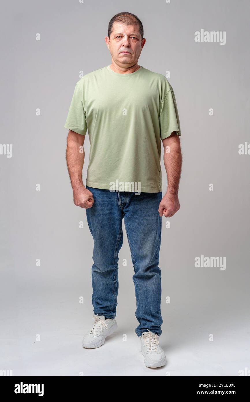 Man in casual attire standing posed against a neutral background ...