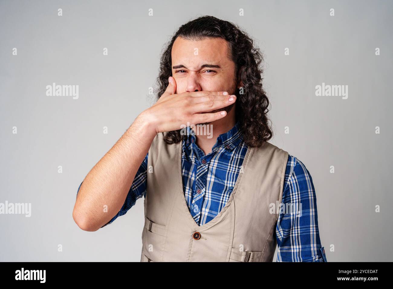 Man making a funny face while pinching his nose in a studio setting ...