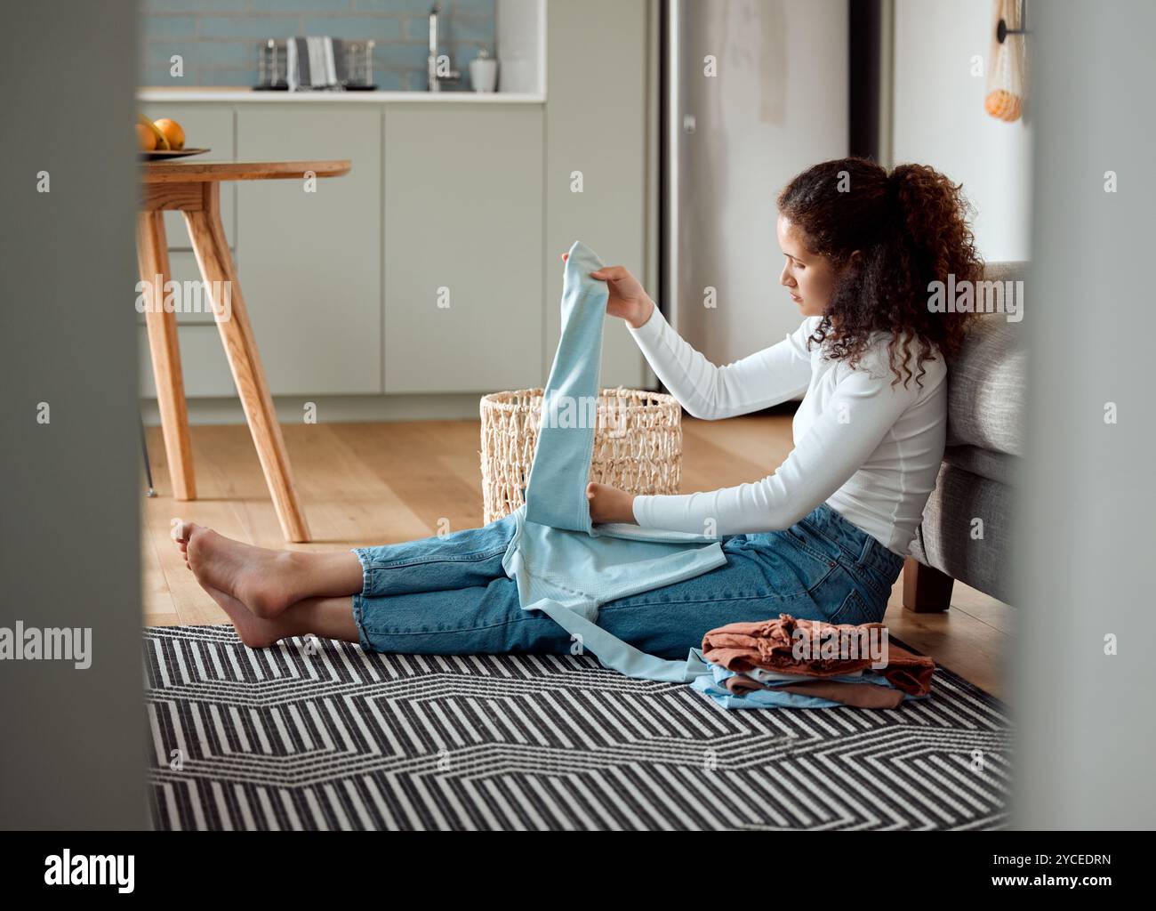 Laundry, relax and woman in home with clothes, housework and weekend ...