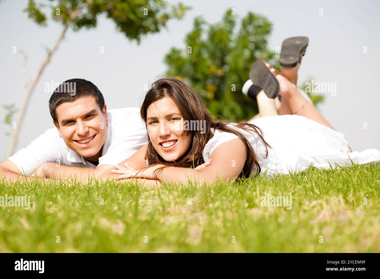 Beautiful young Couple lie down on grass and smile Stock Photo - Alamy