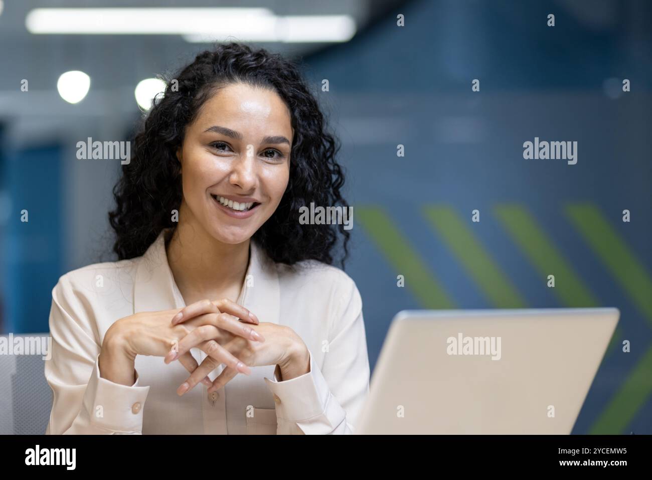 Confident Hispanic woman in office setting smiling at camera. Embracing ...