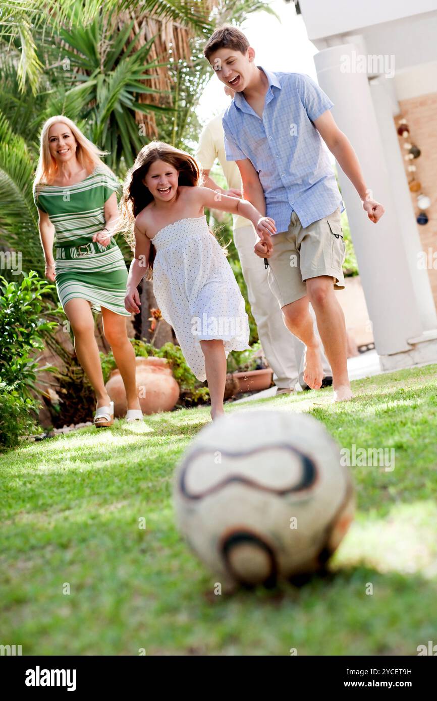 Cute girl rushing towards football as her brother and mom follow her ...