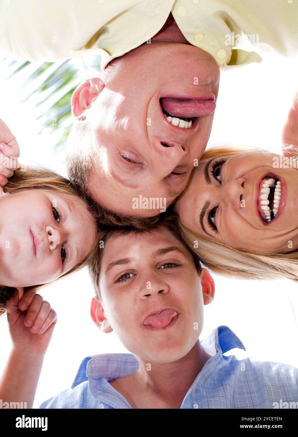 Happy family of four in huddle making weird faces and smiling at camera ...