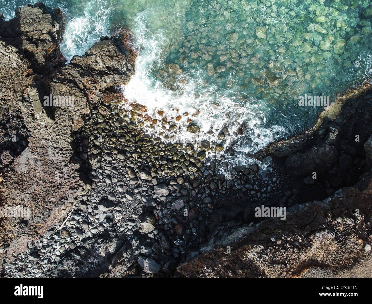 Aerial top view of rocks and sea waves in a volcanic landscape with ...