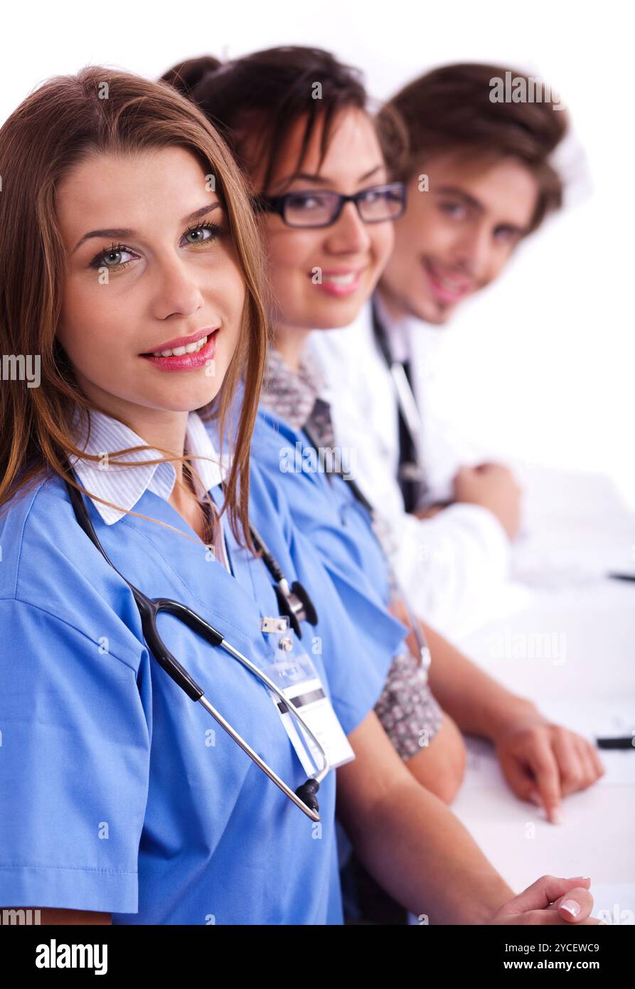 Medical staff sitting in a row against white background and looking at ...