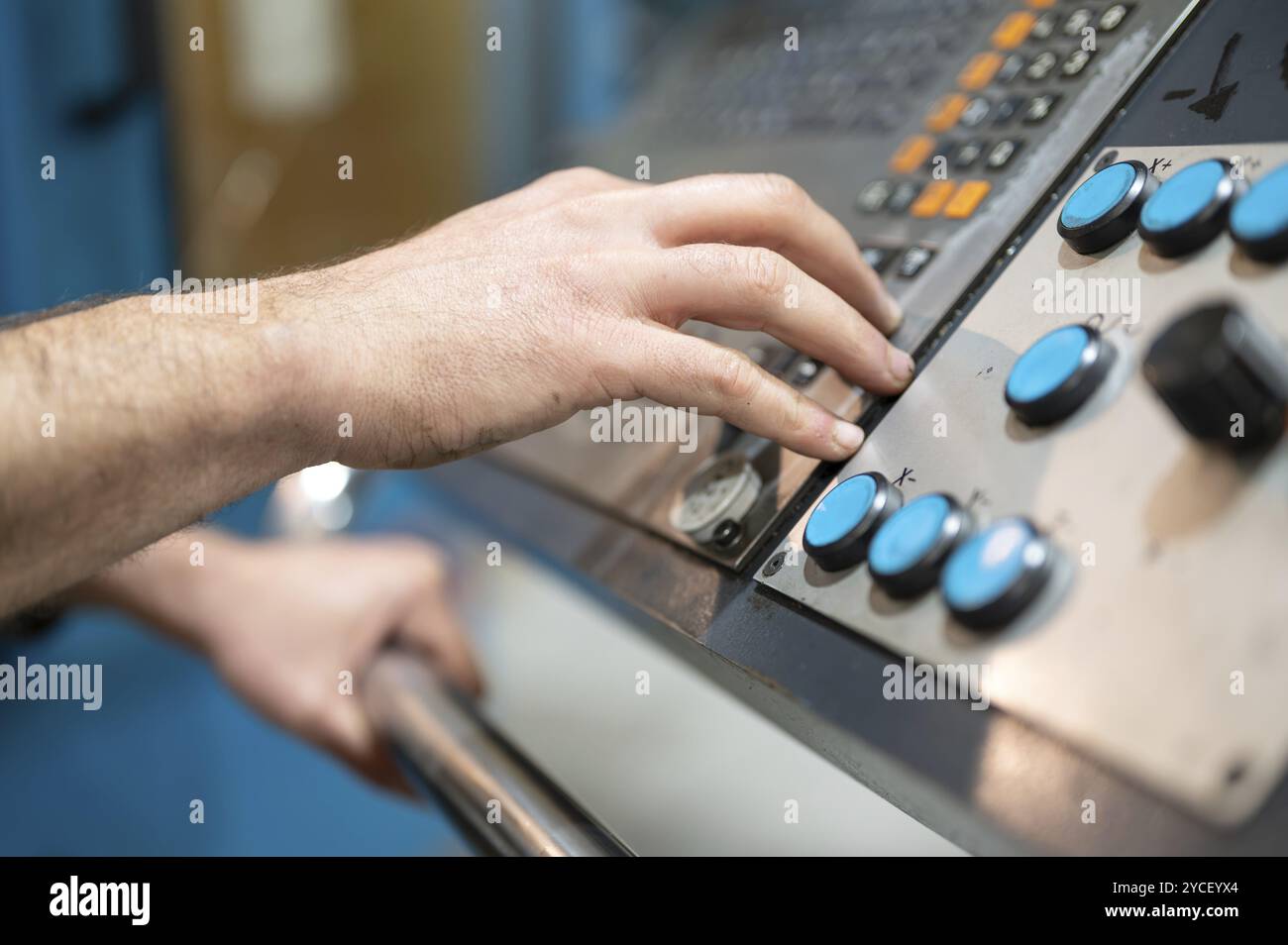 Worker pressing buttons on CNC machine control board in factory. graphy ...