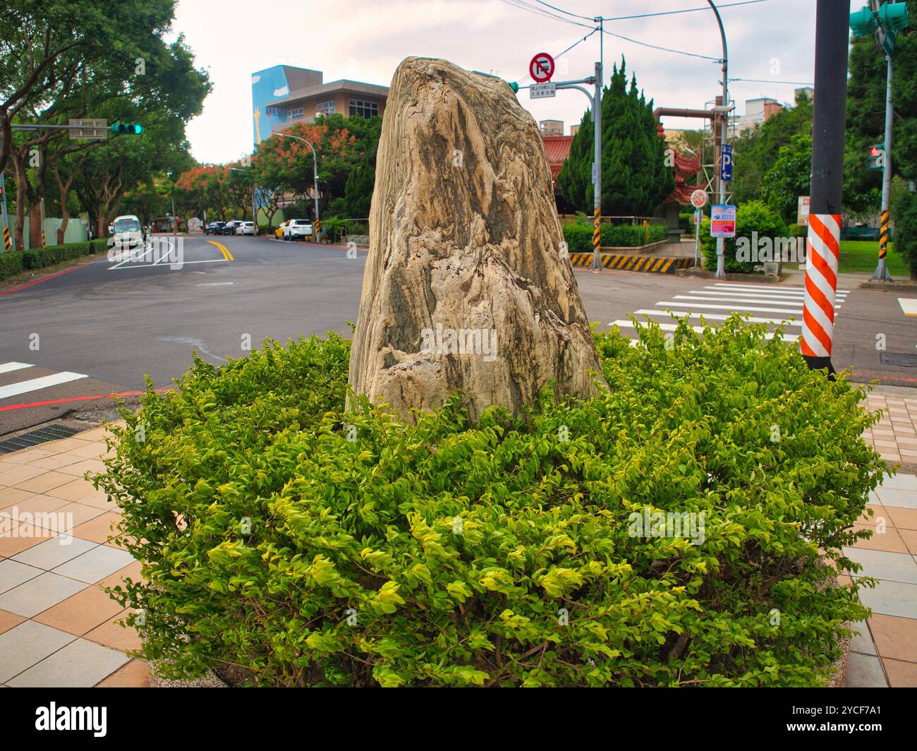 A massive, textured stone stands in the center of a small roundabout ...