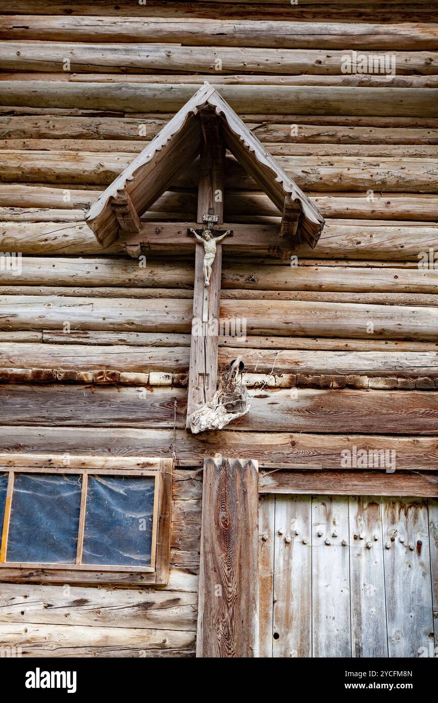 Traditional roofed house cross on a barn wall made of round beams ...