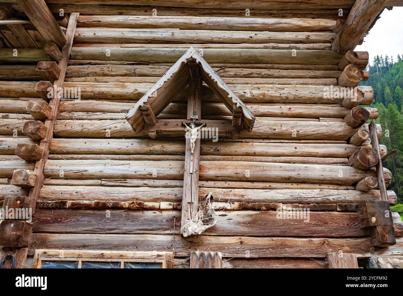 Traditional roofed house cross on a barn wall made of round beams ...