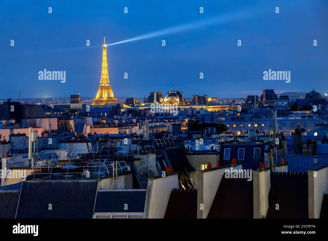 Eiffel tower lights and beacon and the roofs of Paris illuminated at ...