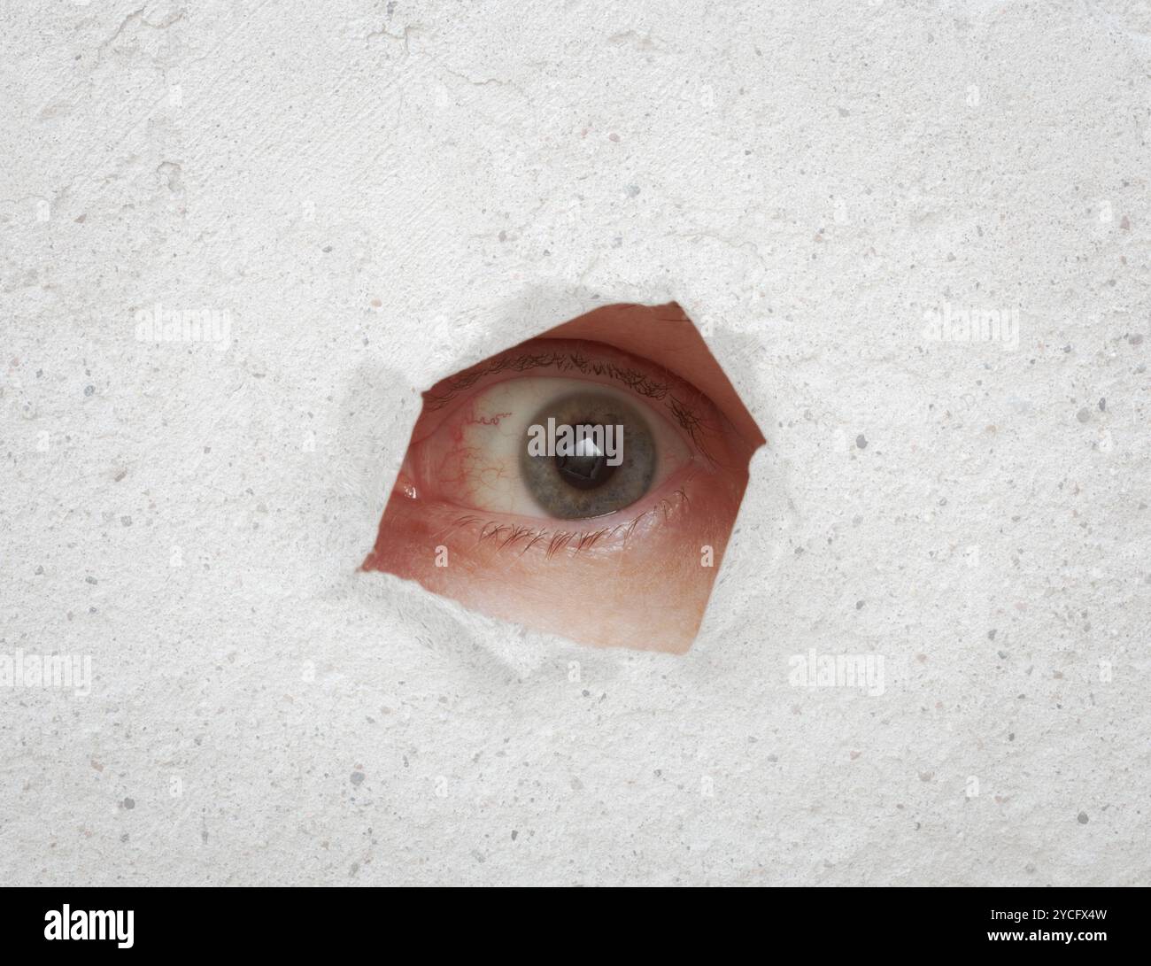 Eye looking through hole in gray wall Stock Photo - Alamy