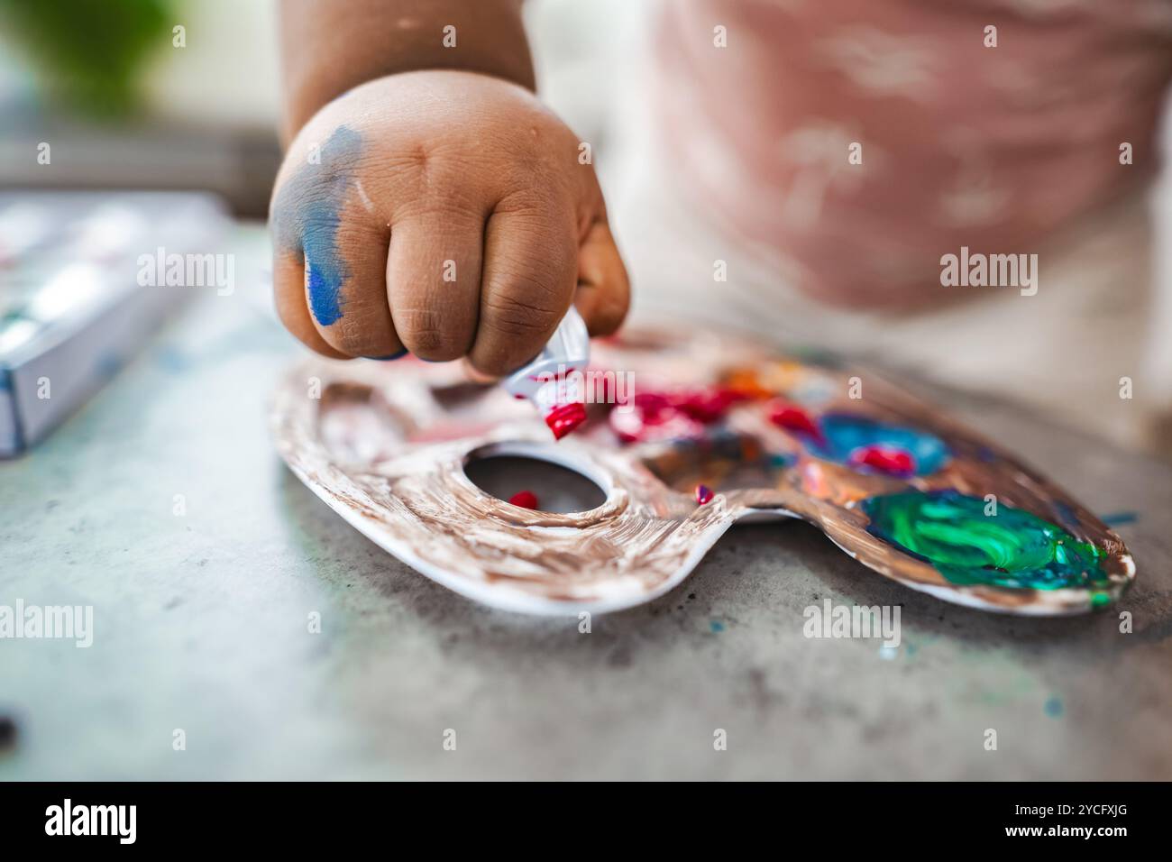 Young artist exploring colors with paint on a palette Stock Photo - Alamy