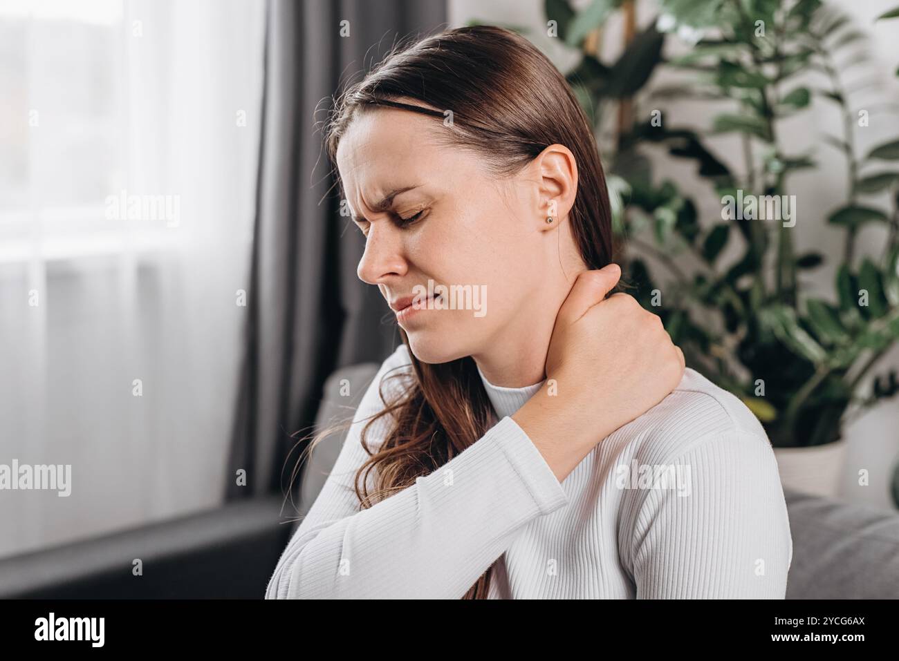 Sad young woman painful with neck pain body ache from work, holding ...