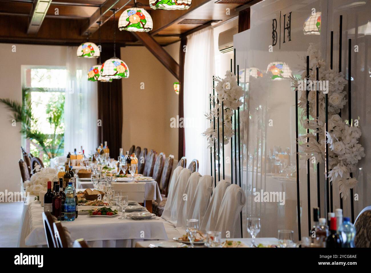Elegant Banquet Hall Set for a Celebration with Floral Arrangements and Stained Glass Lighting ...