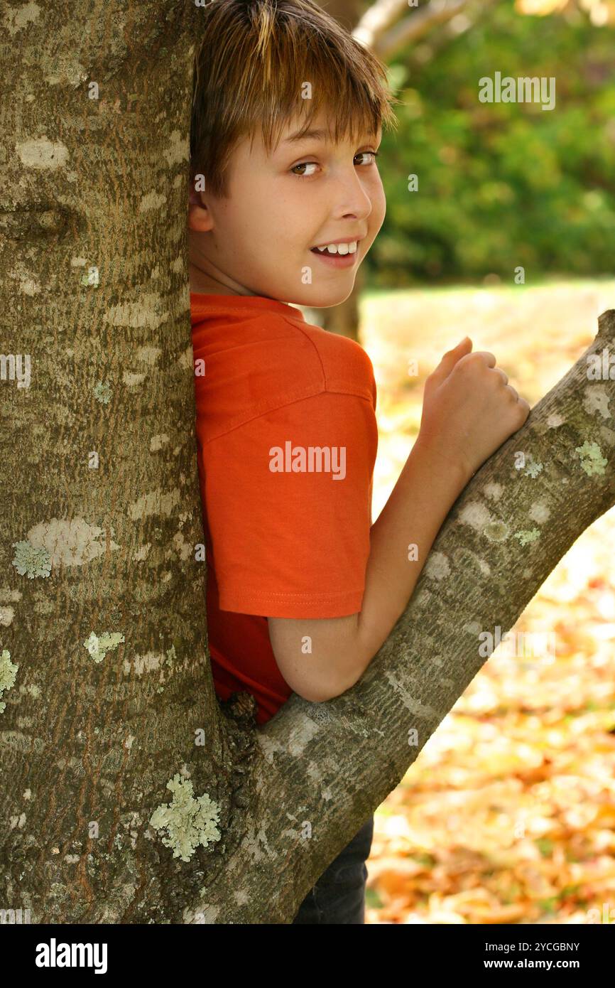 Boy leaning against a tree Stock Photo - Alamy