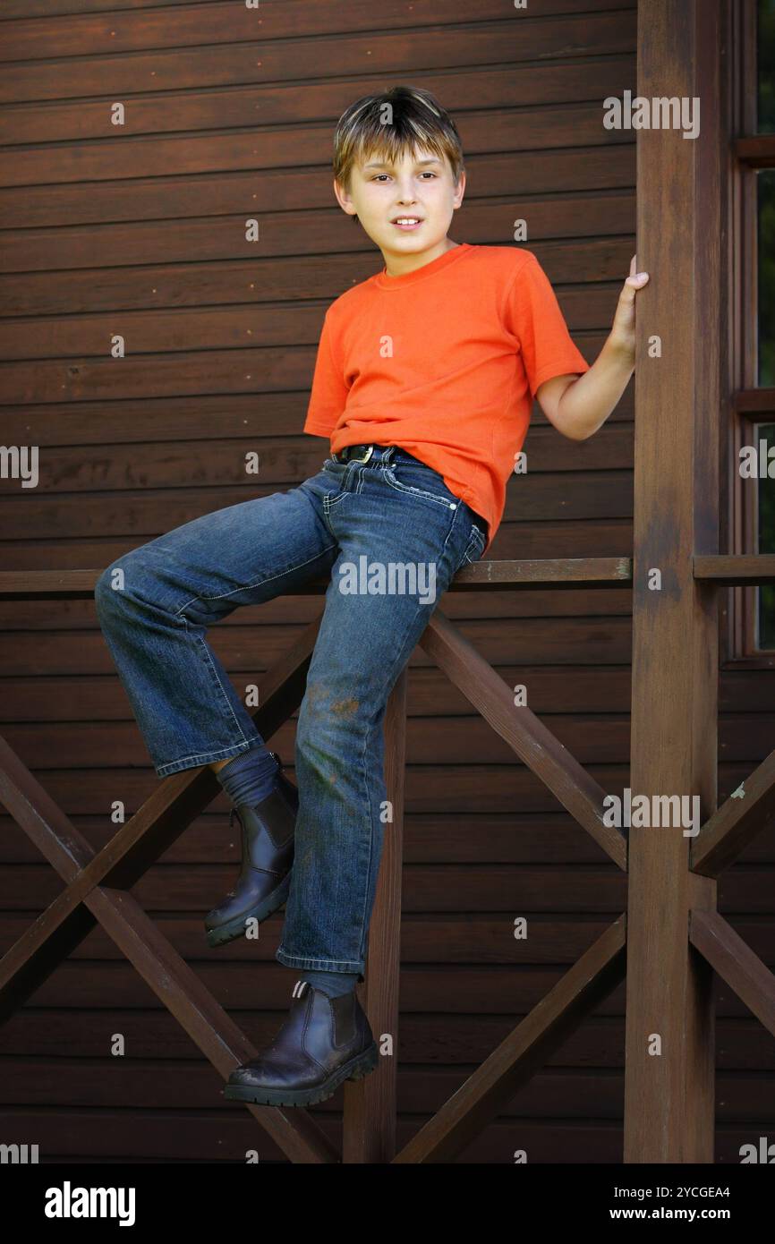 A child sits on the timber balustrade of a verandah Stock Photo - Alamy