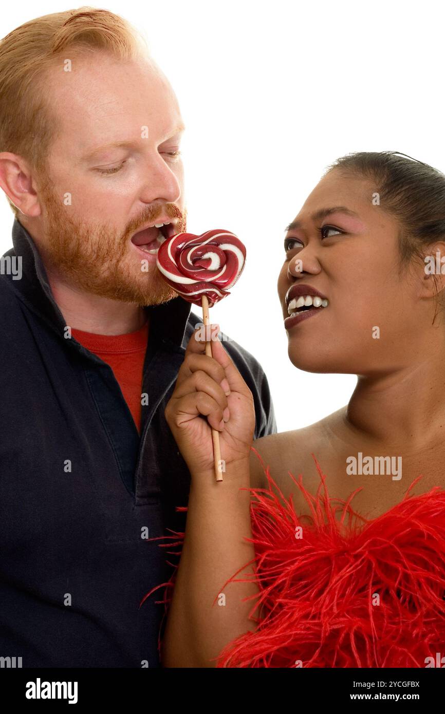 Couple sharing a red heart lollipop candy Stock Photo - Alamy