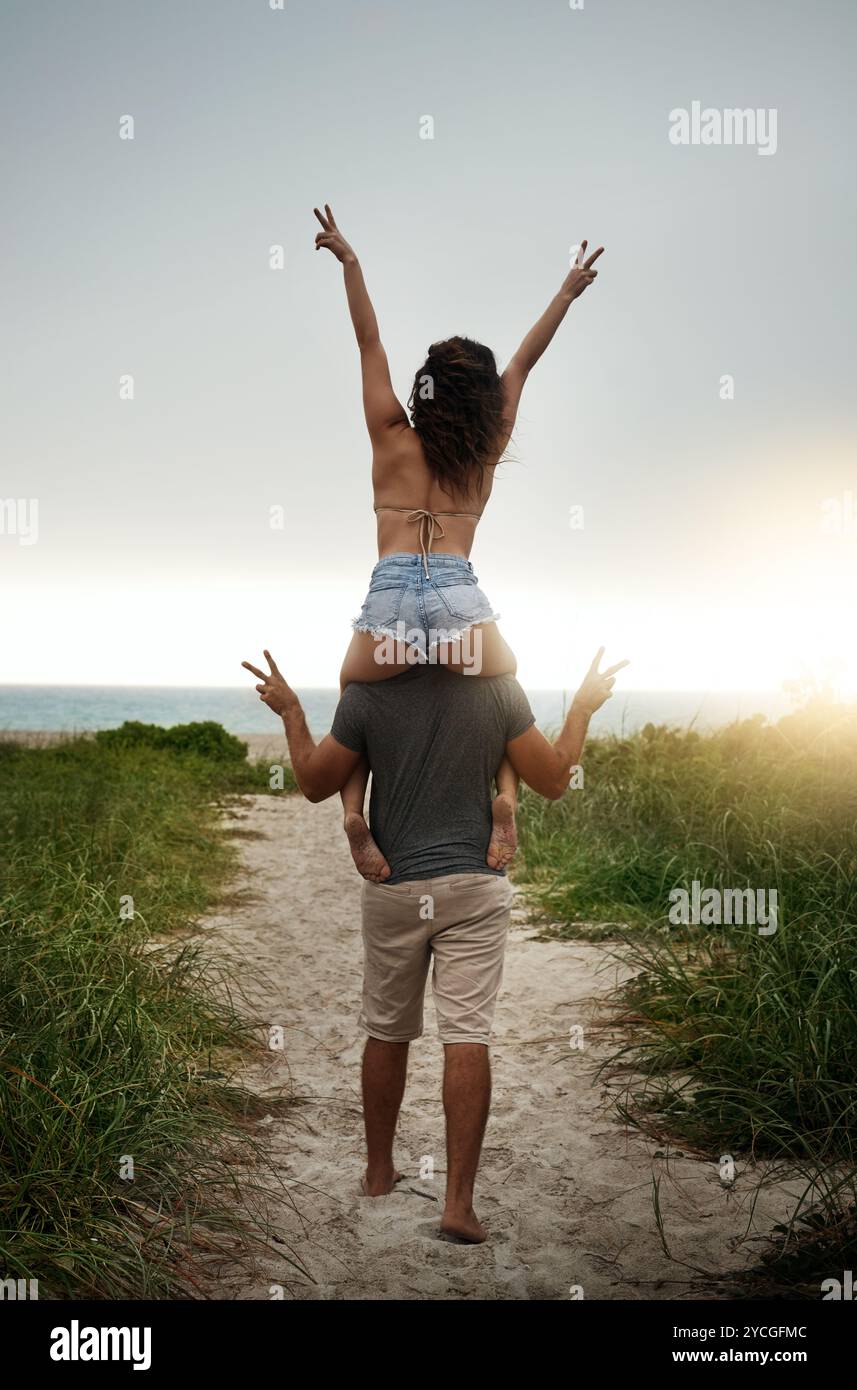 Piggyback, peace sign and back of couple, outdoor and holiday for ...