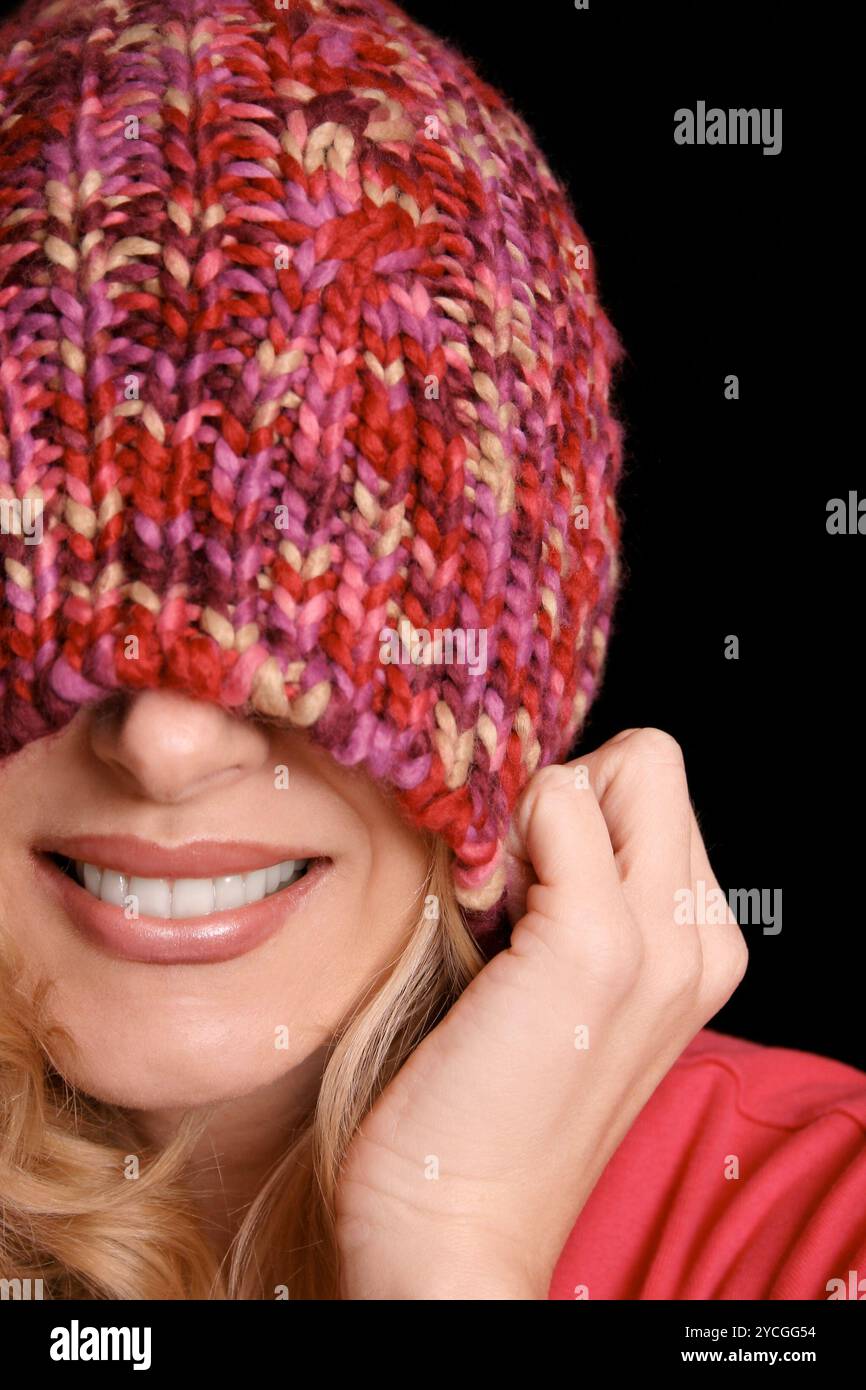 Girl pulls woollen beanie over face in playful manner Stock Photo - Alamy