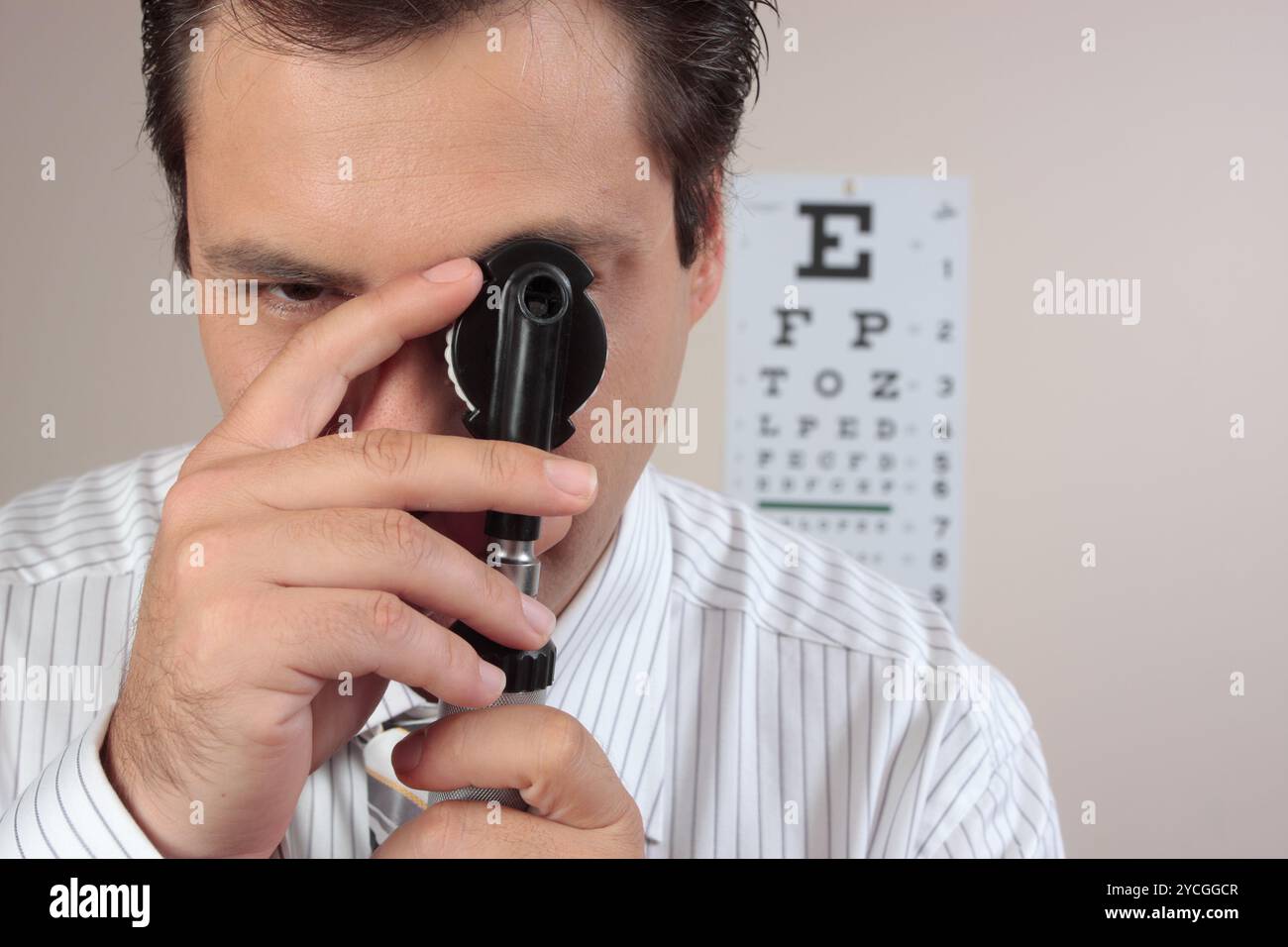 An optometrist turning the lens dial of the opthalmoscope while ...