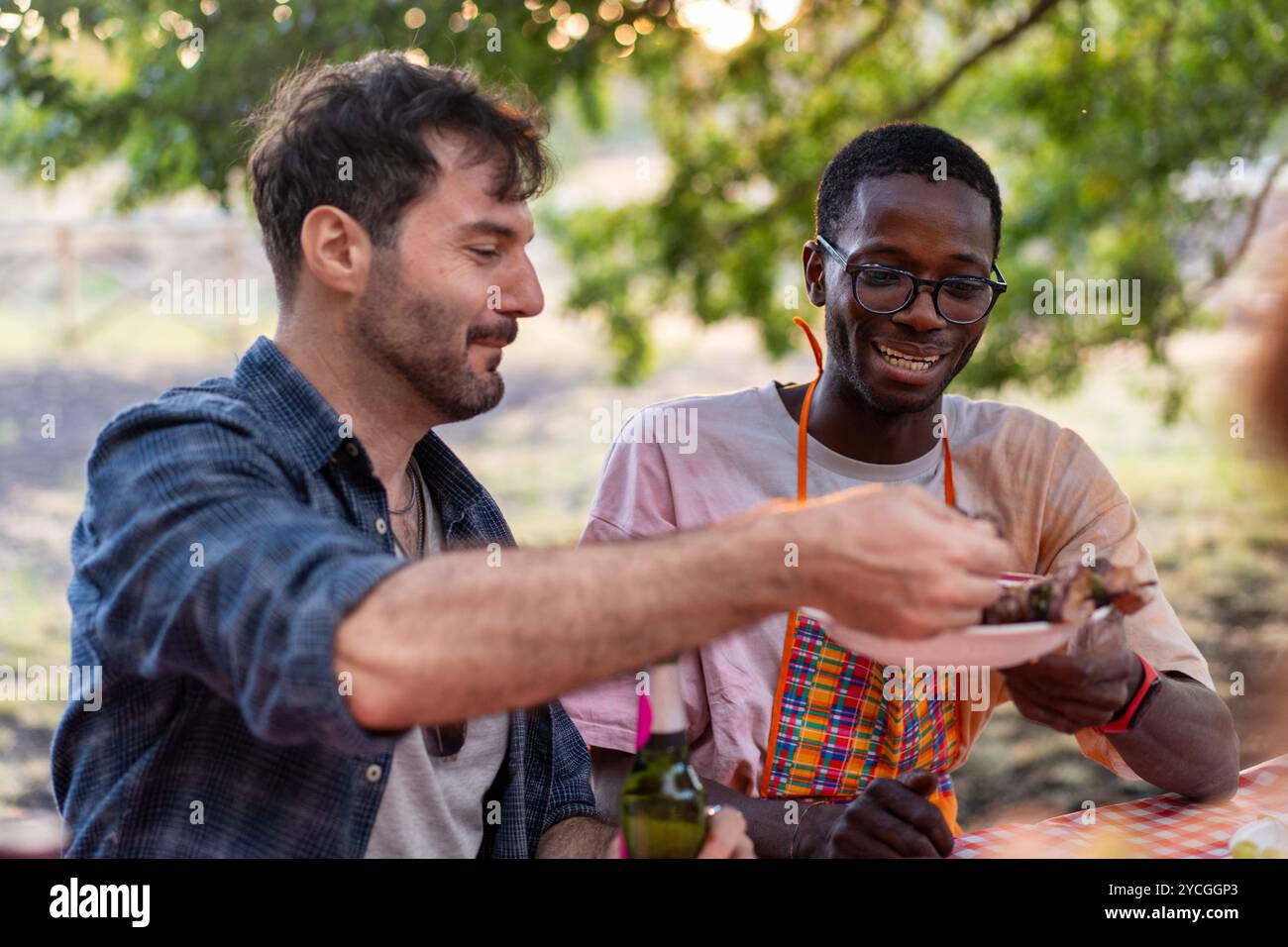 Multiracial friends enjoying barbecue party outdoors. Candid moment of ...