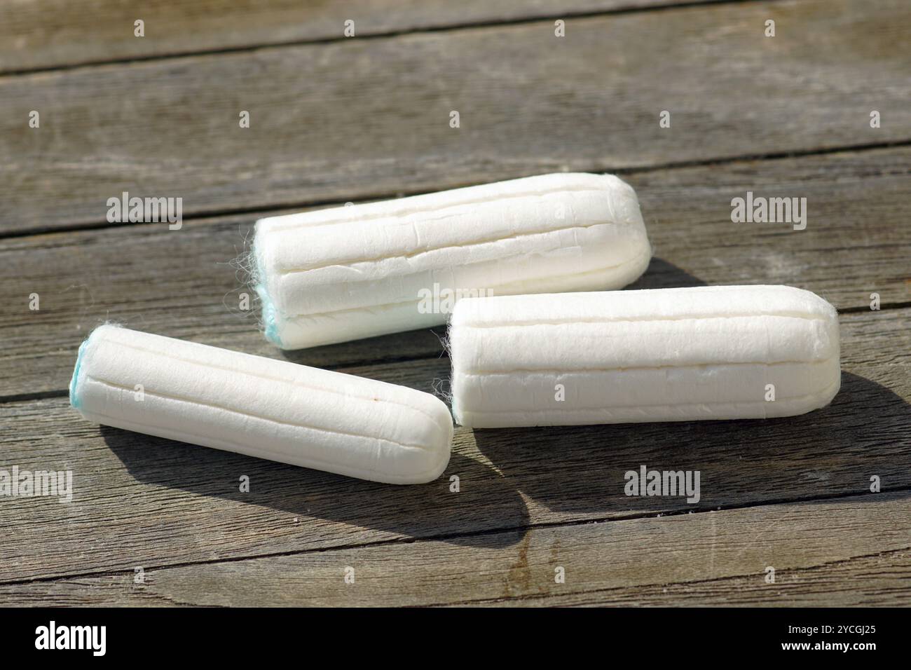Two large tampons and one medium sized tampon lying on a wooden table ...