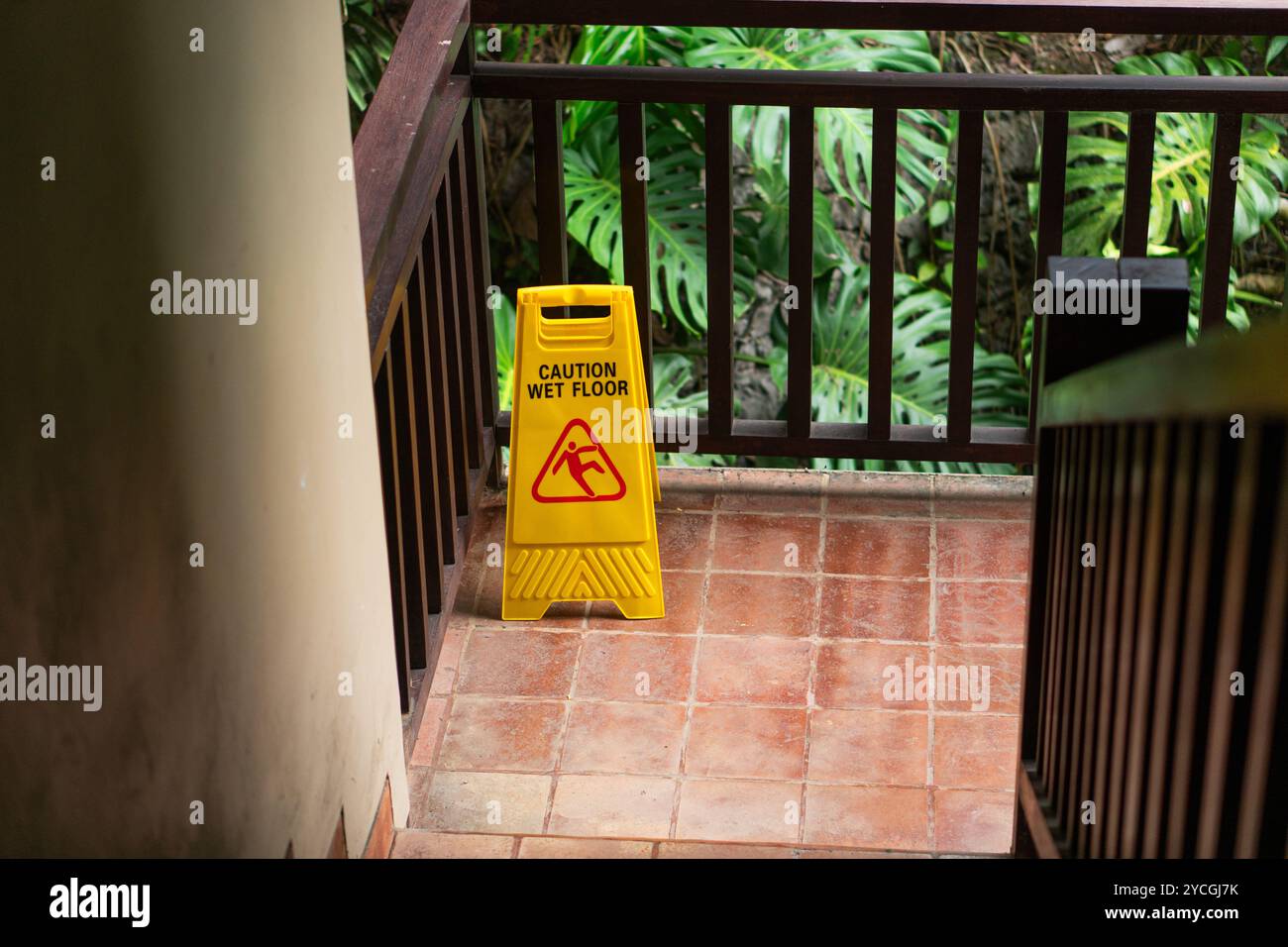 A bright yellow caution sign indicating a wet floor, positioned in a ...