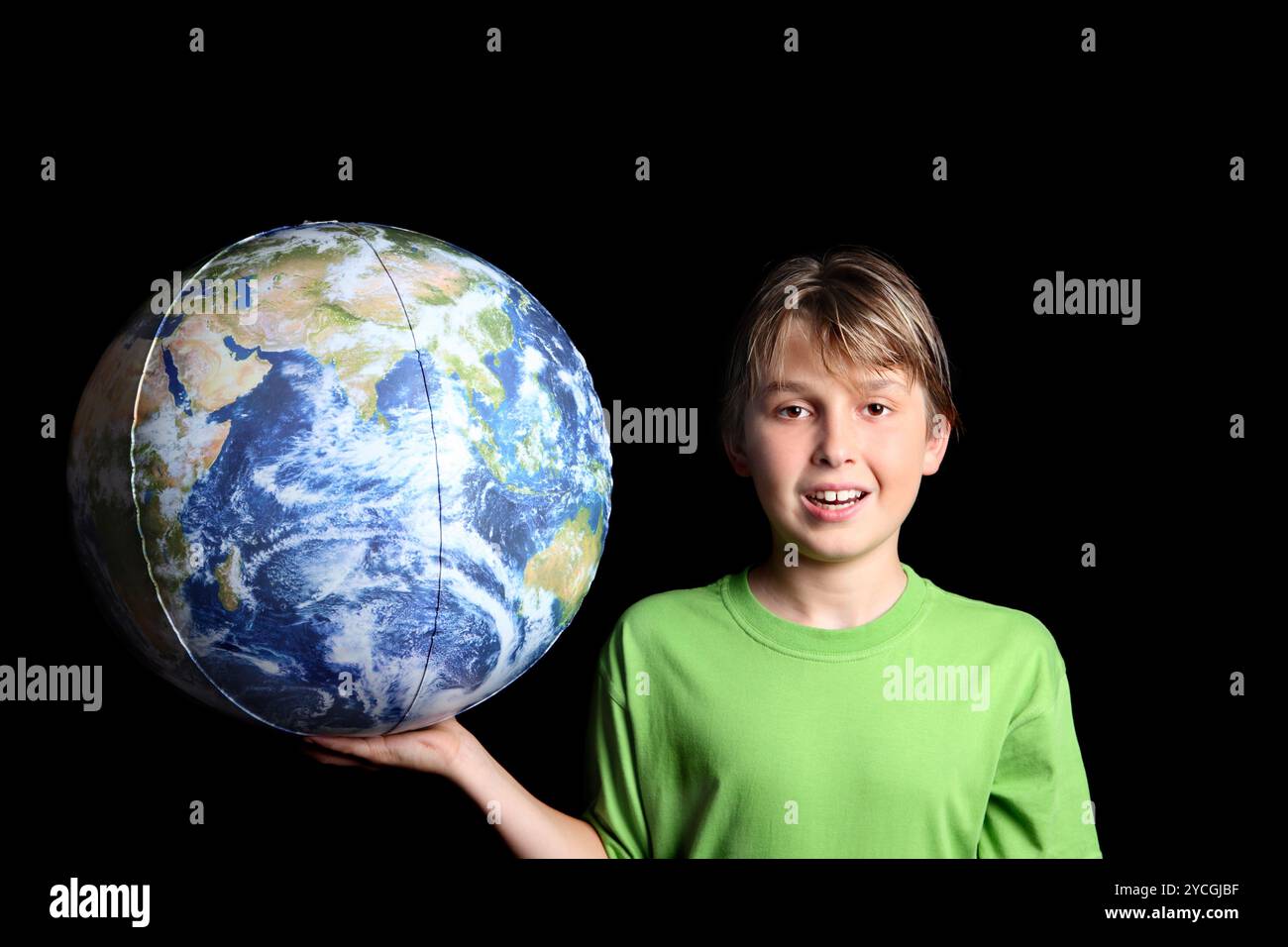 A young boy holding the earth world ball in his hand against a black ...