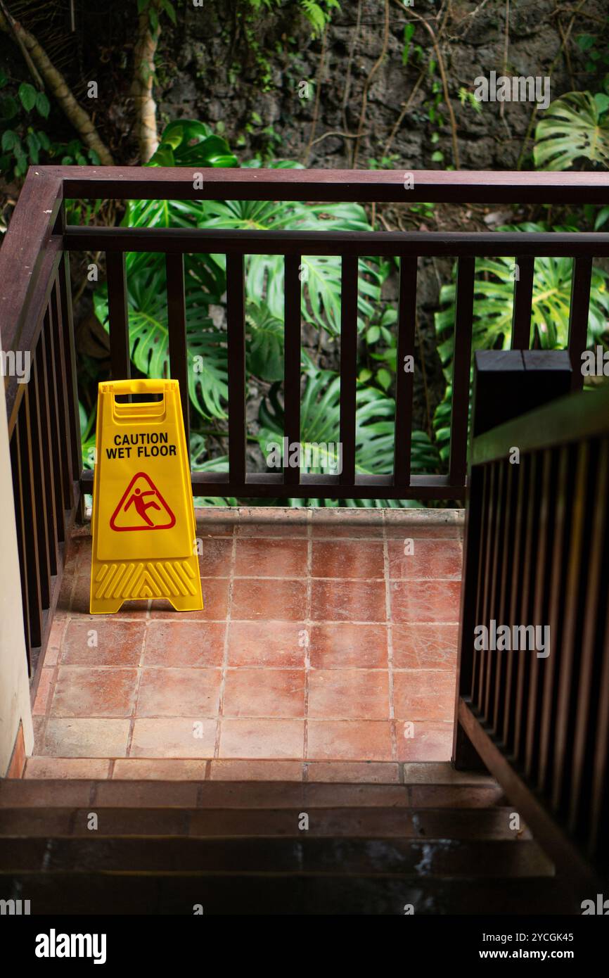 A bright yellow caution sign indicating a wet floor, positioned in a ...