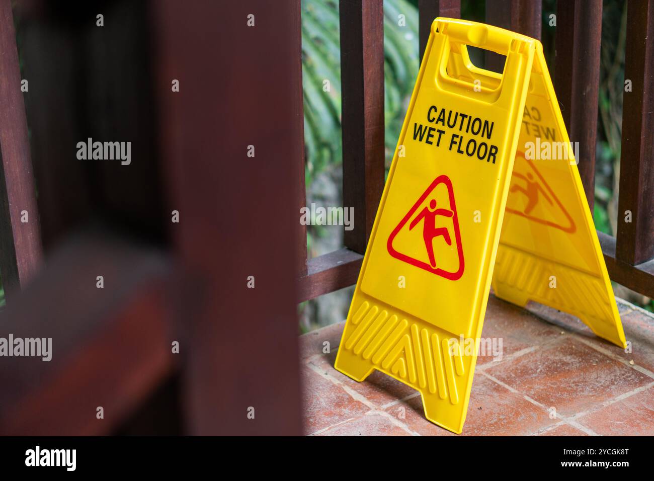 A bright yellow caution sign indicating a wet floor, positioned in a ...