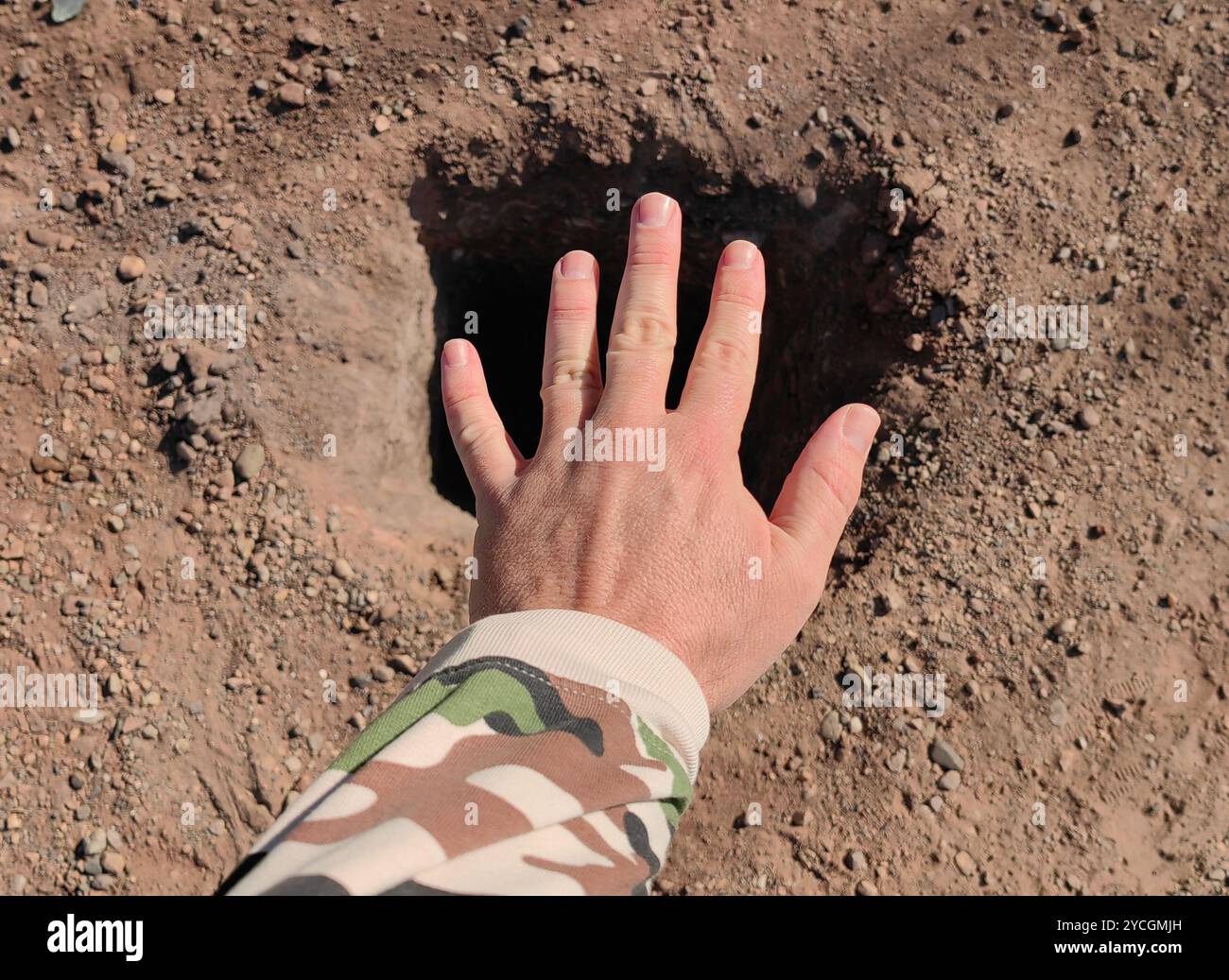Grounded Connection: Man's Hand Framed by a Square-Shaped Dig Hole, Reaching to Touch the Earth ...
