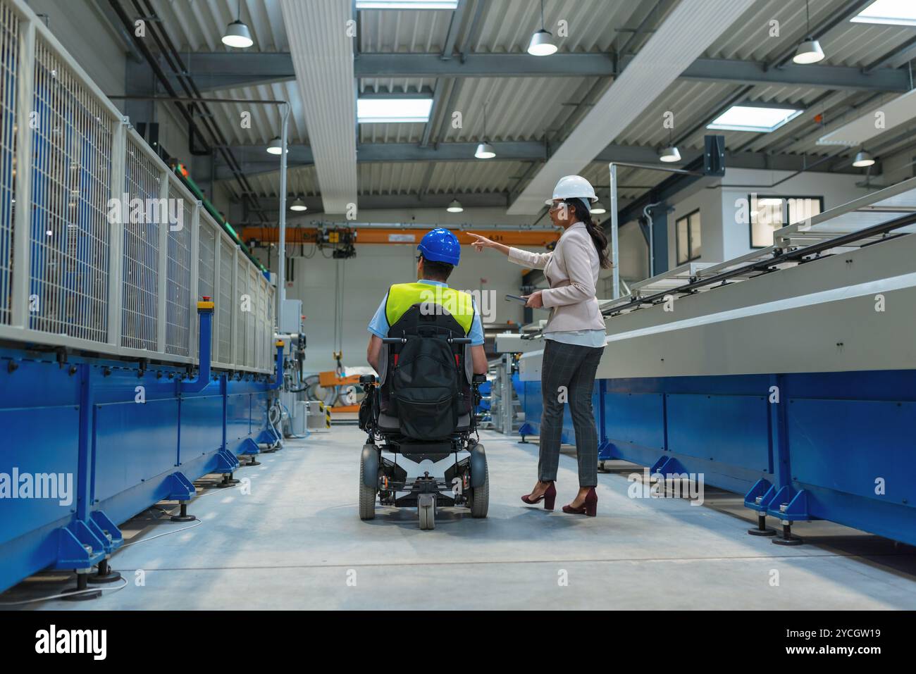 Female production manager and male worker on wheelchair during an ...