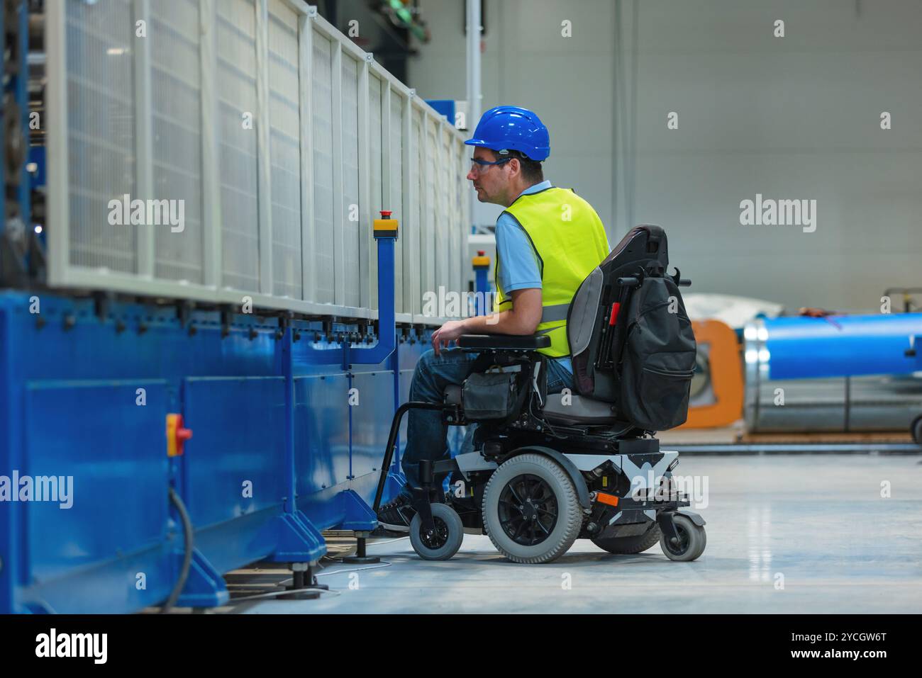 Man with disability in yellow vest, engineer in a factory unit checking ...