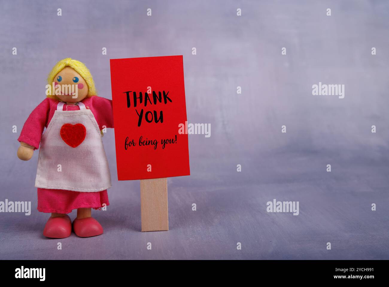 A wooden doll holds a red sign with a motivational message, promoting ...