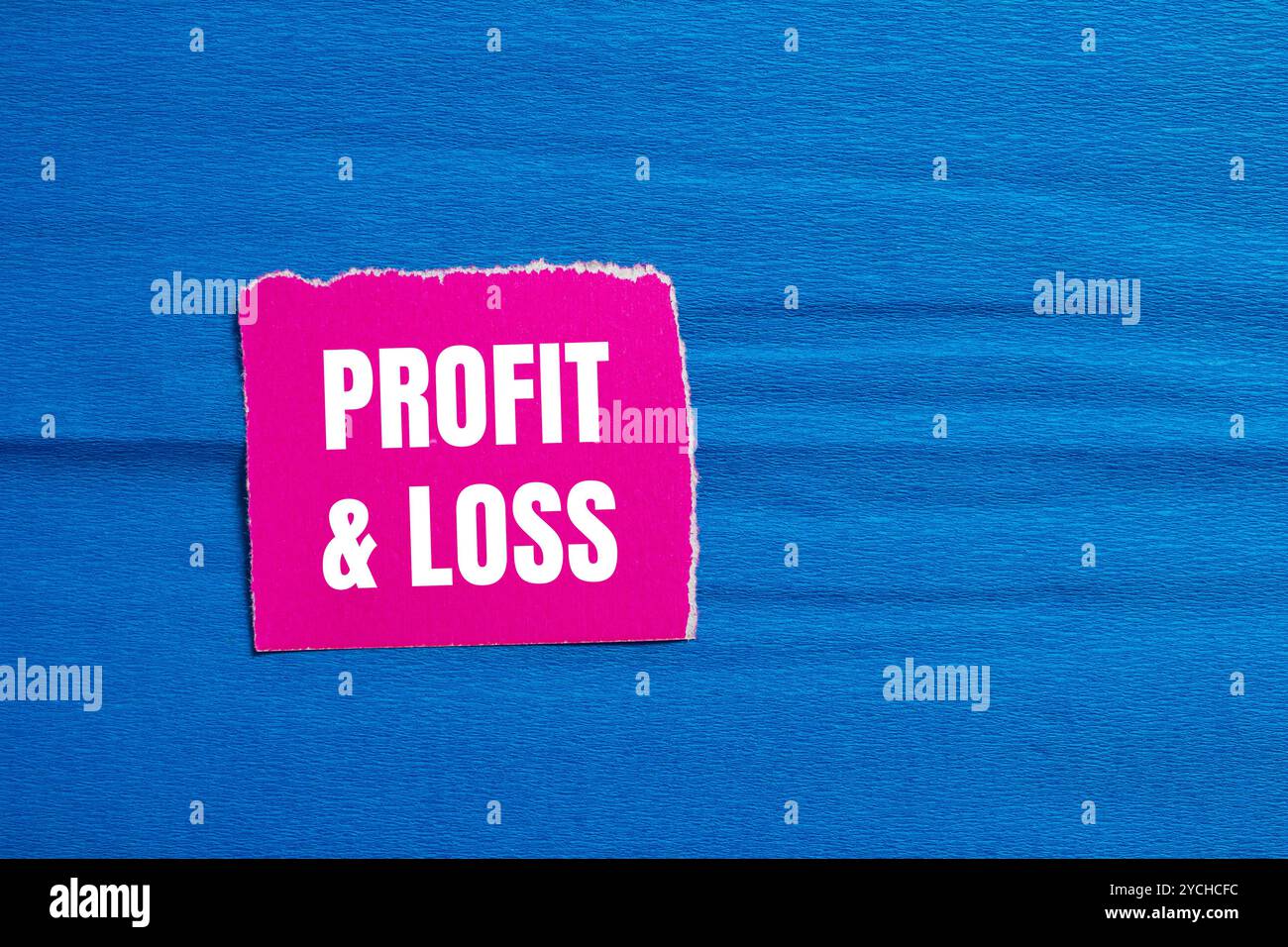 Profit and loss message written on ripped pink torn paper piece with ...